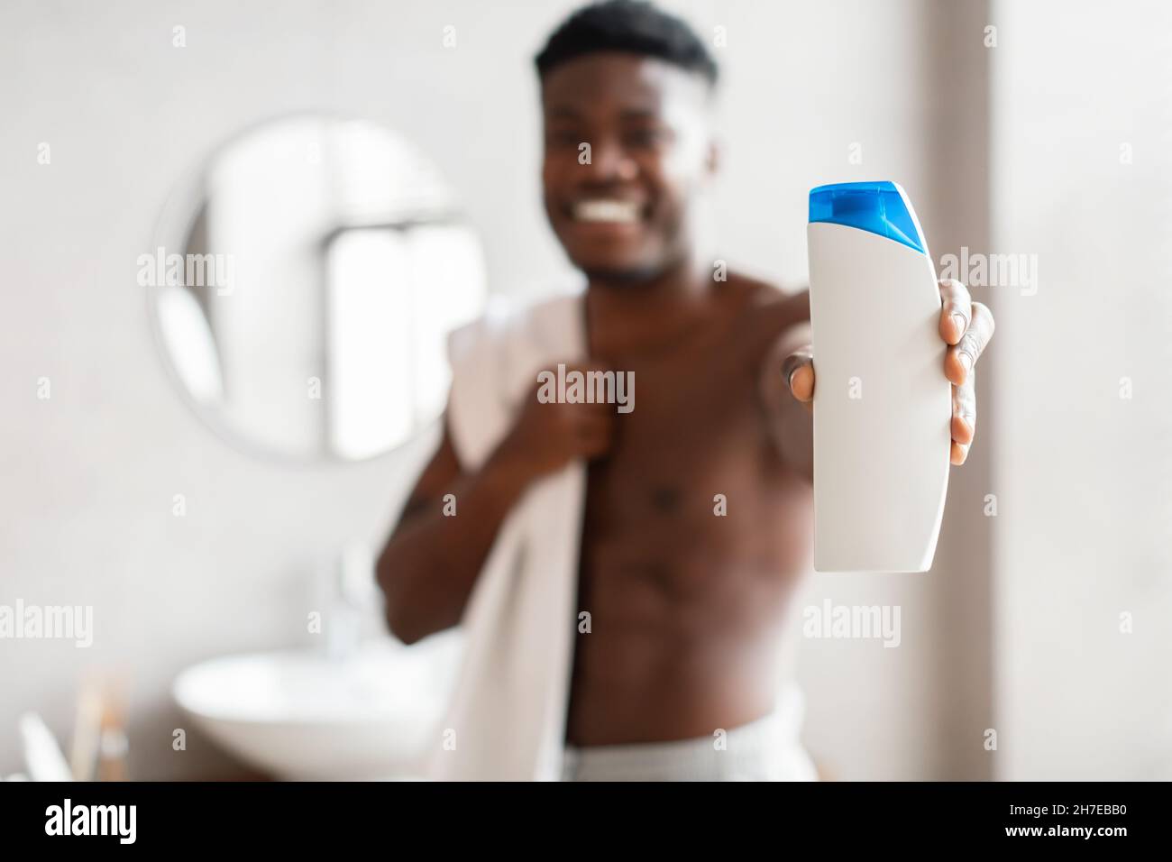 African American Man Showing Shampoo Bottle Standing In Modern Bathroom ...