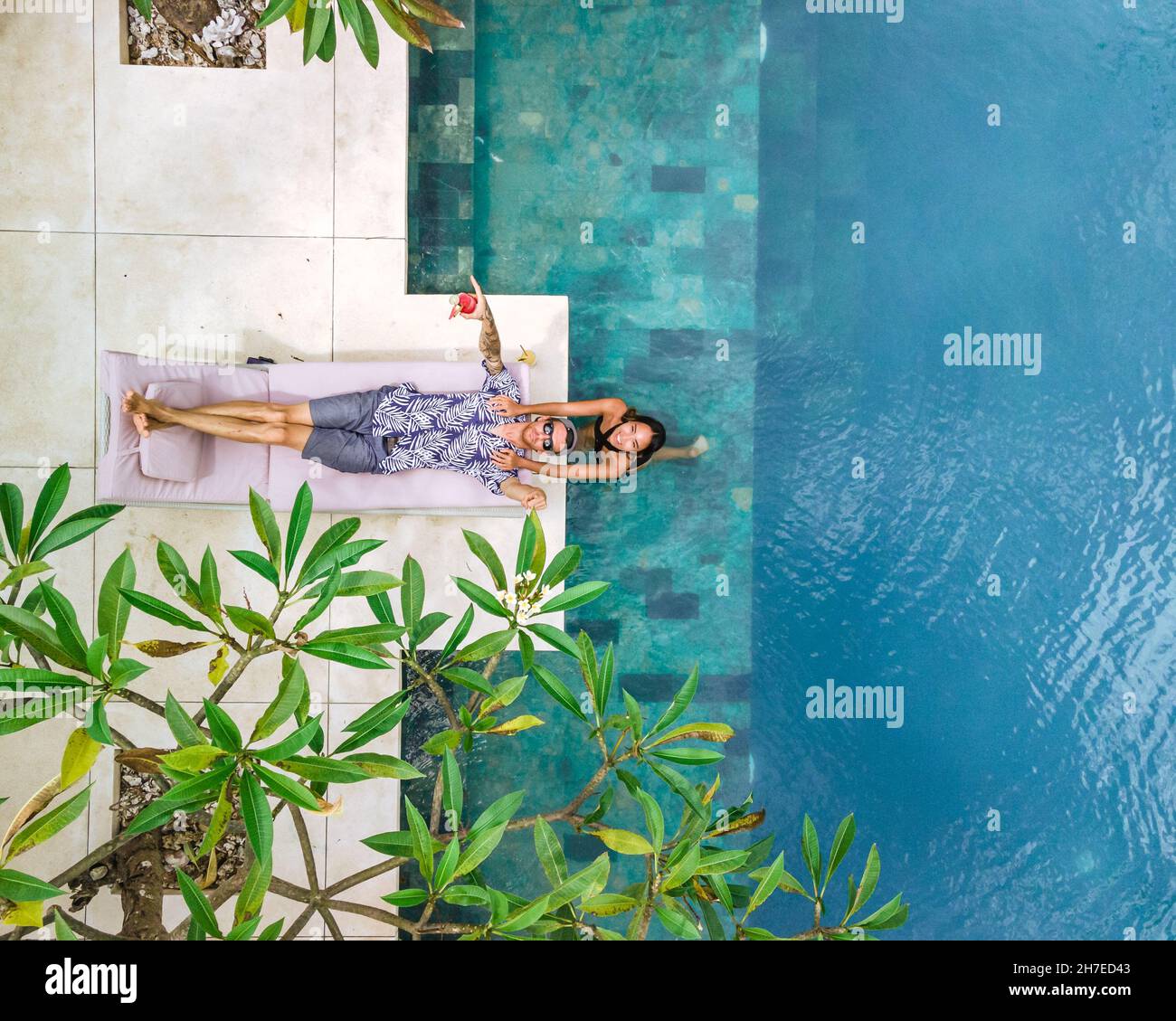 Top view shot of a couple chilling in the pool during the day in ...