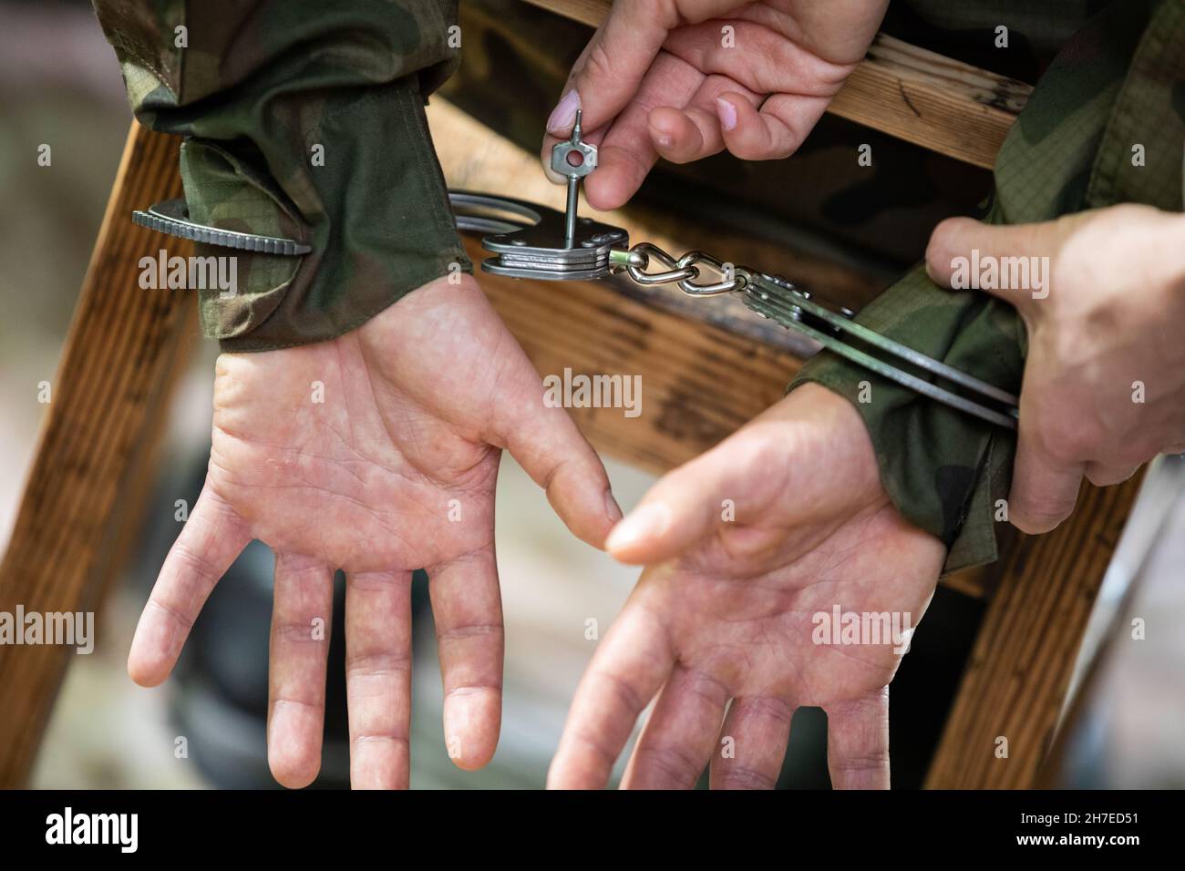 A guard unlocks the handcuffs of an accused soldier with a small key ...