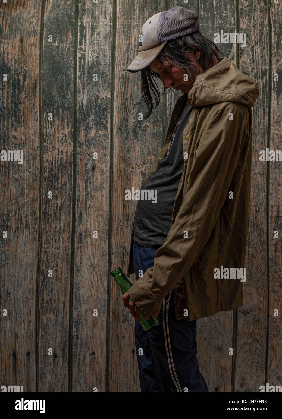 Junkie man with cap green anorak and blue sweatpants near wooden old ...