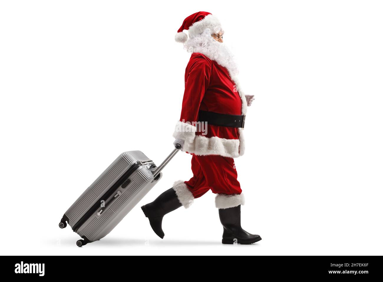 Full length profile shot of santa claus walking and pulling a suitcase ...