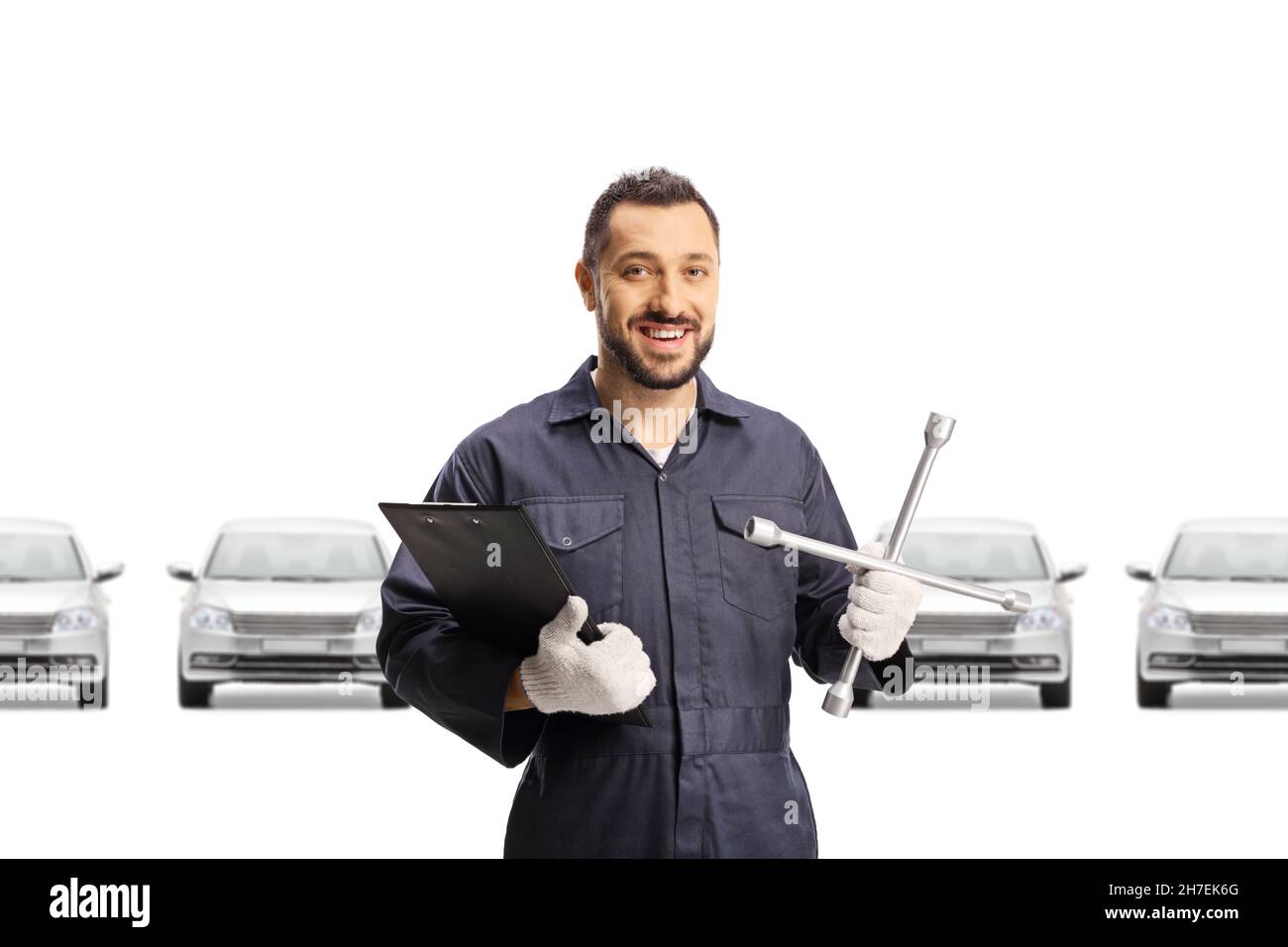 Auto mechanic worker holding a lug wrench in front of silver cars ...