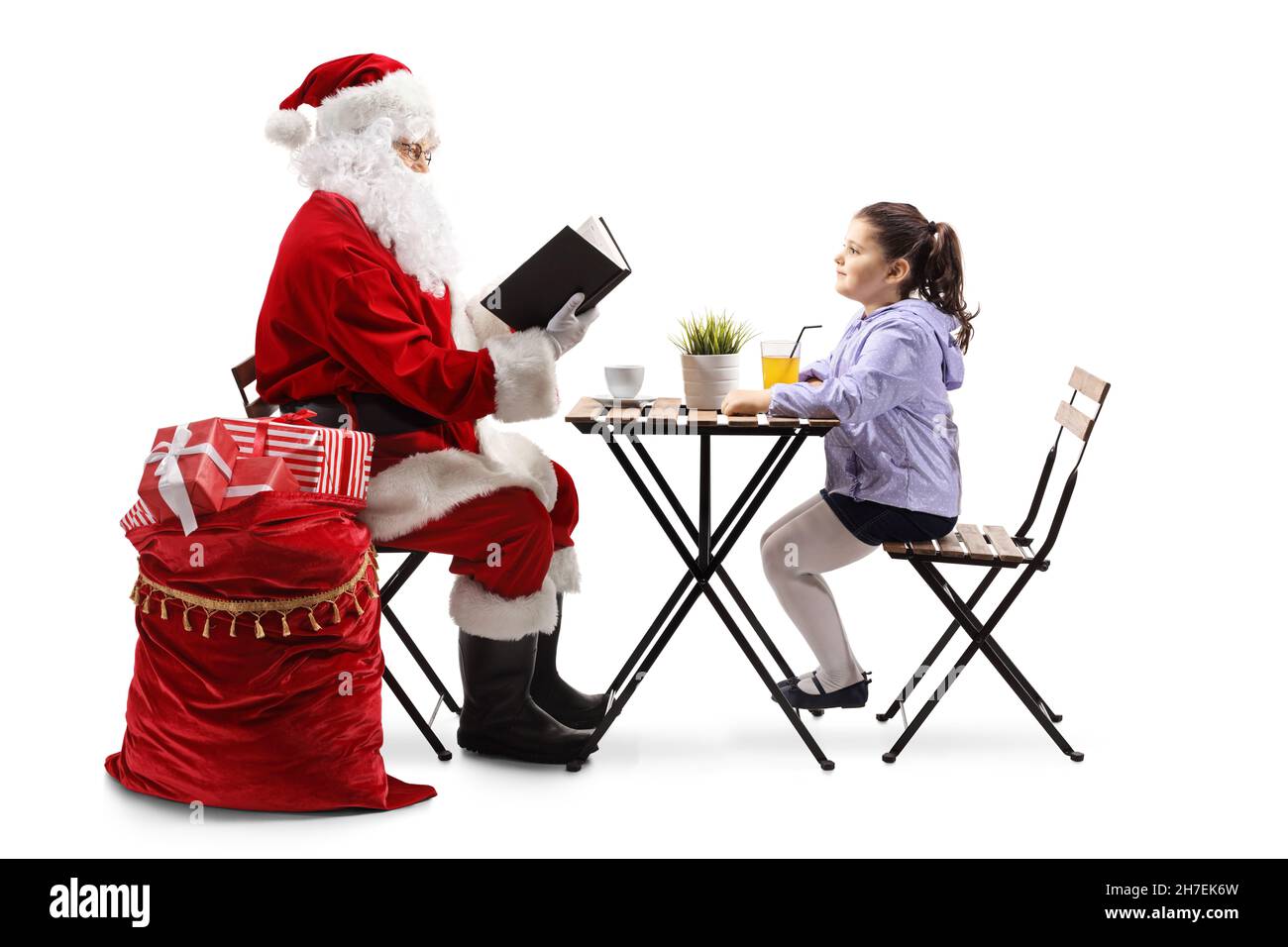 Santa Claus sitting at a table and reading a story to a little girl ...