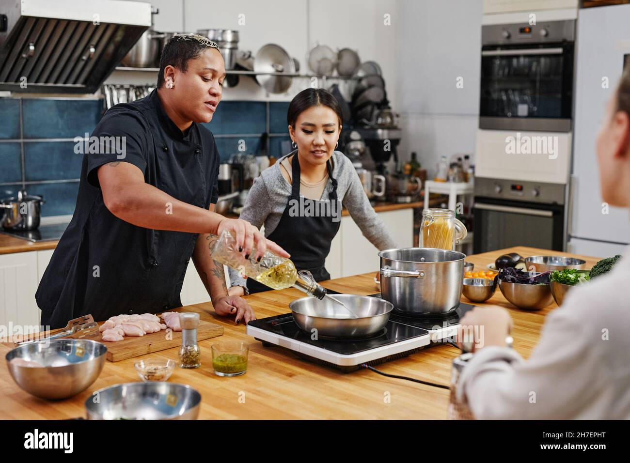 Portrait of female chef frying meat during cooking class in kitchen ...