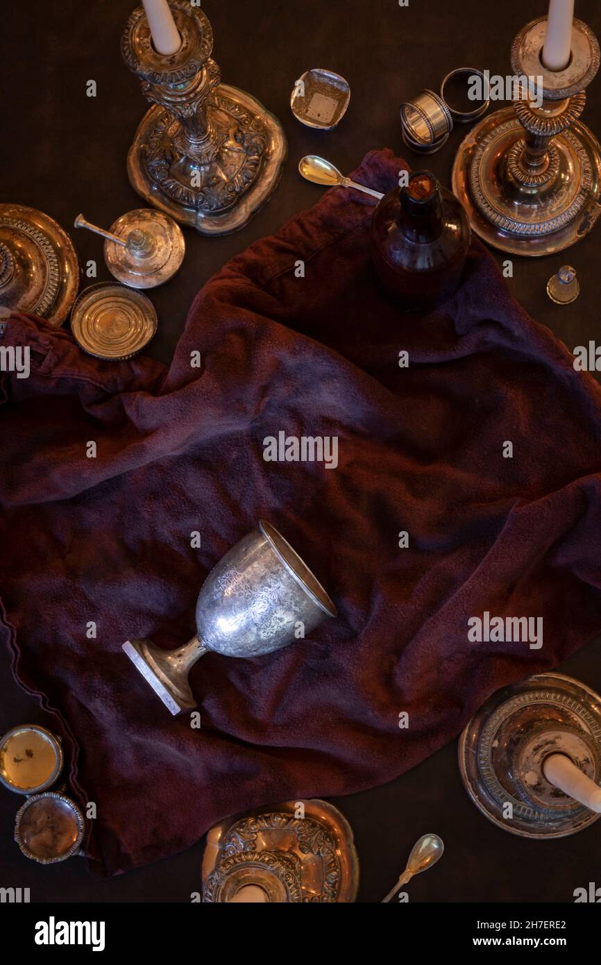 Flat lay view of tipped over silver chalice goblet grail surrounded by ...