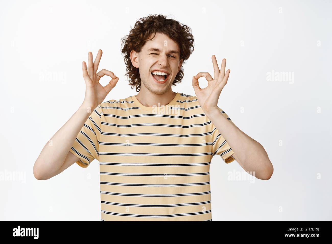 Happy handsome young man showing okay sign, laughing and nod in ...