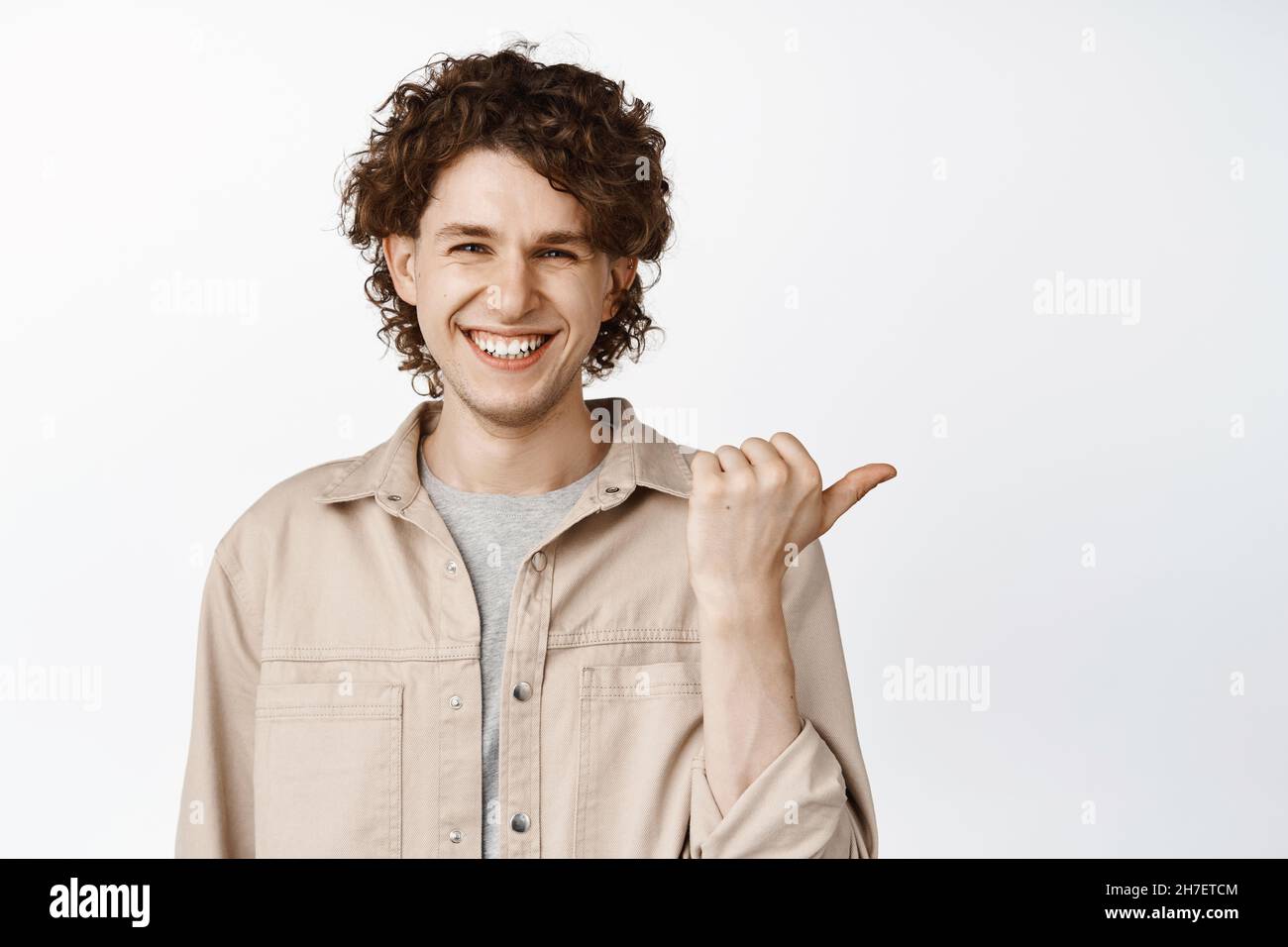 Handsome young man pointing right, smiling and showing advertisement ...