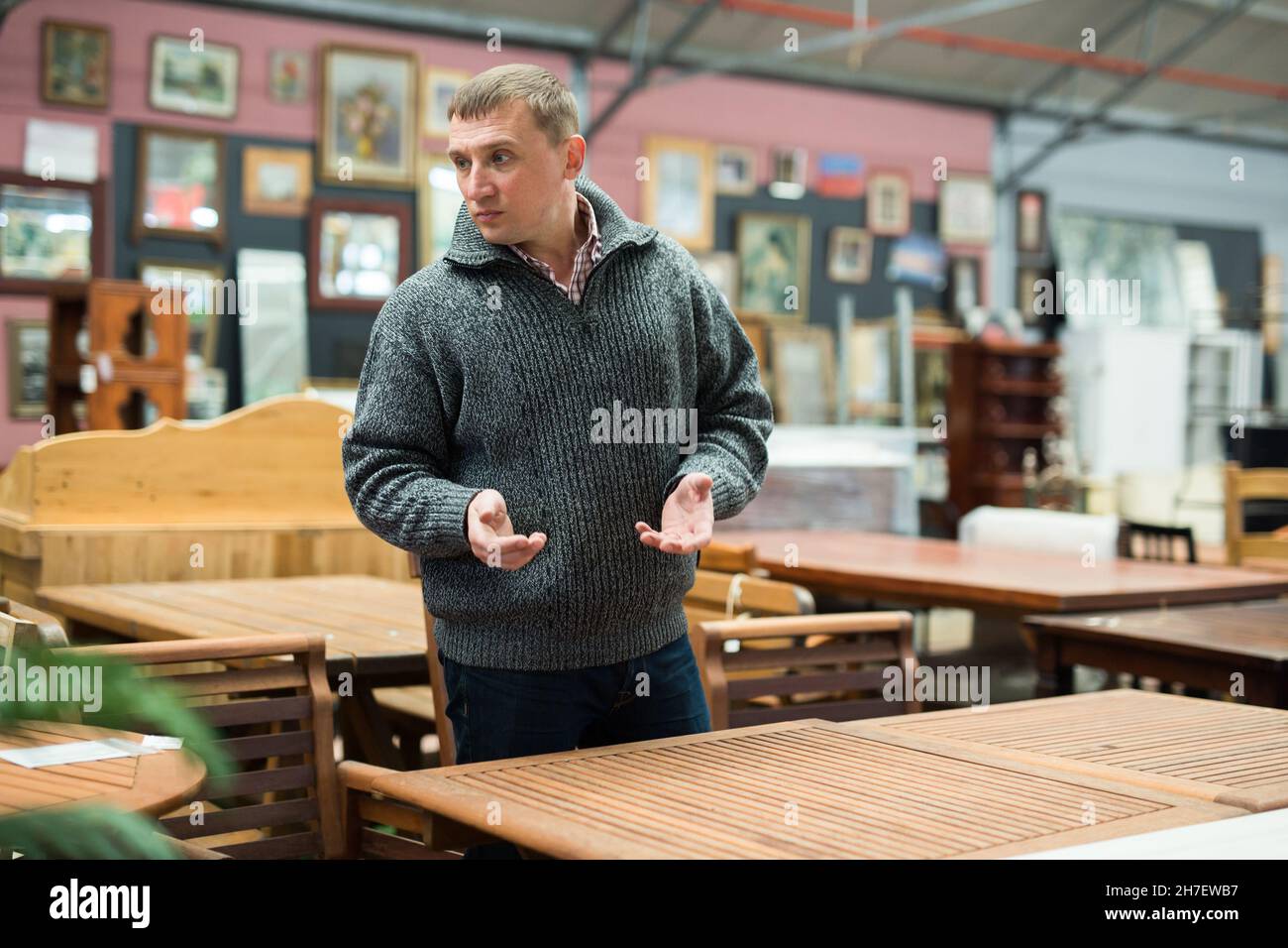 Puzzled man choosing new furniture Stock Photo - Alamy