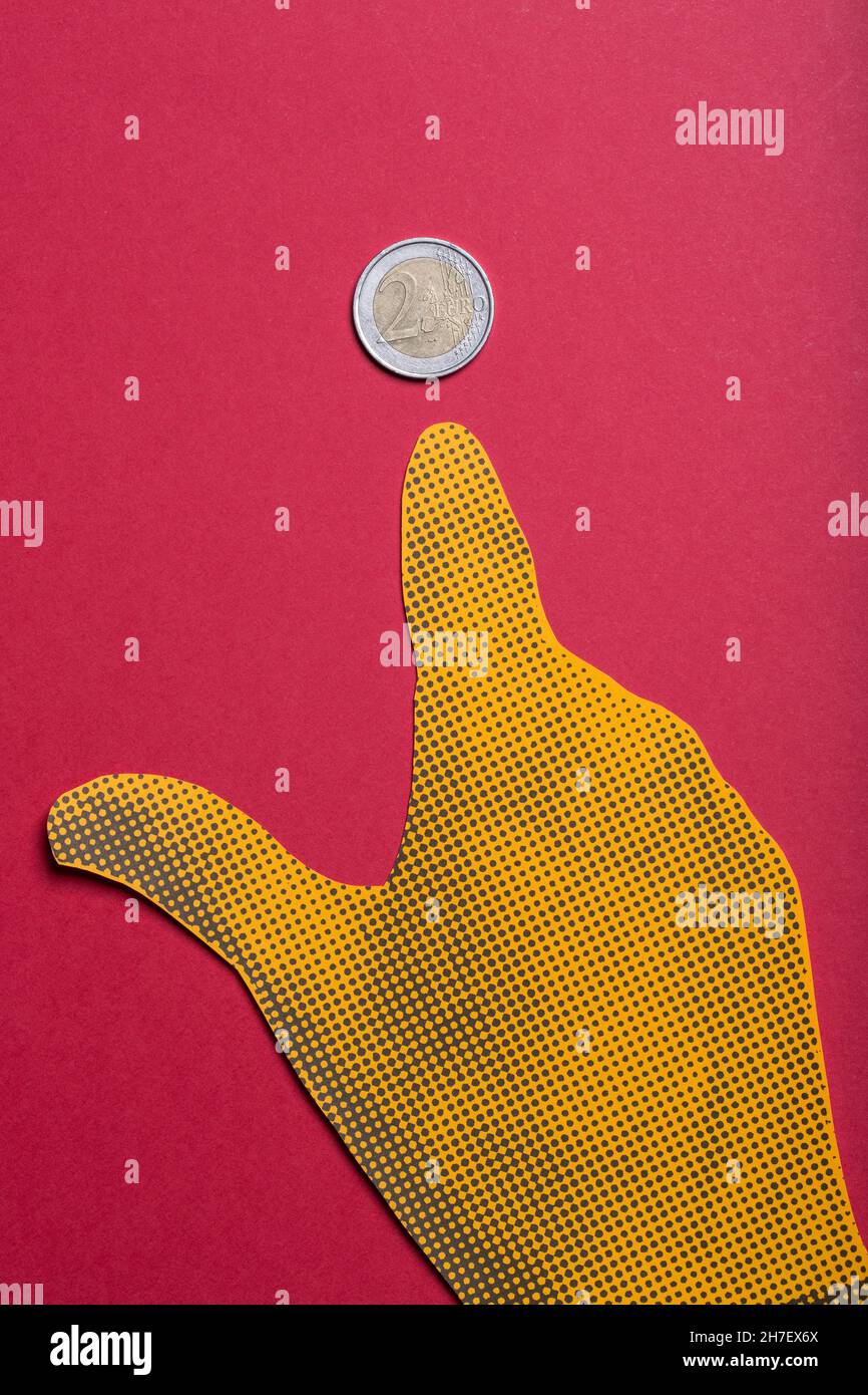 Paper hand points to 2 euro coin Stock Photo - Alamy