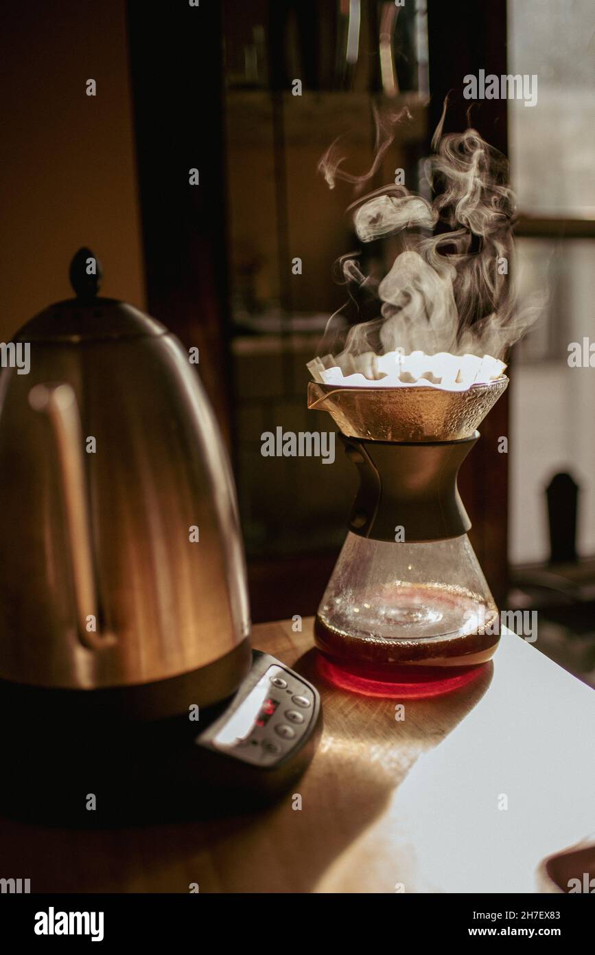 Brewing steaming hot coffee using glass pour over and countertop ...