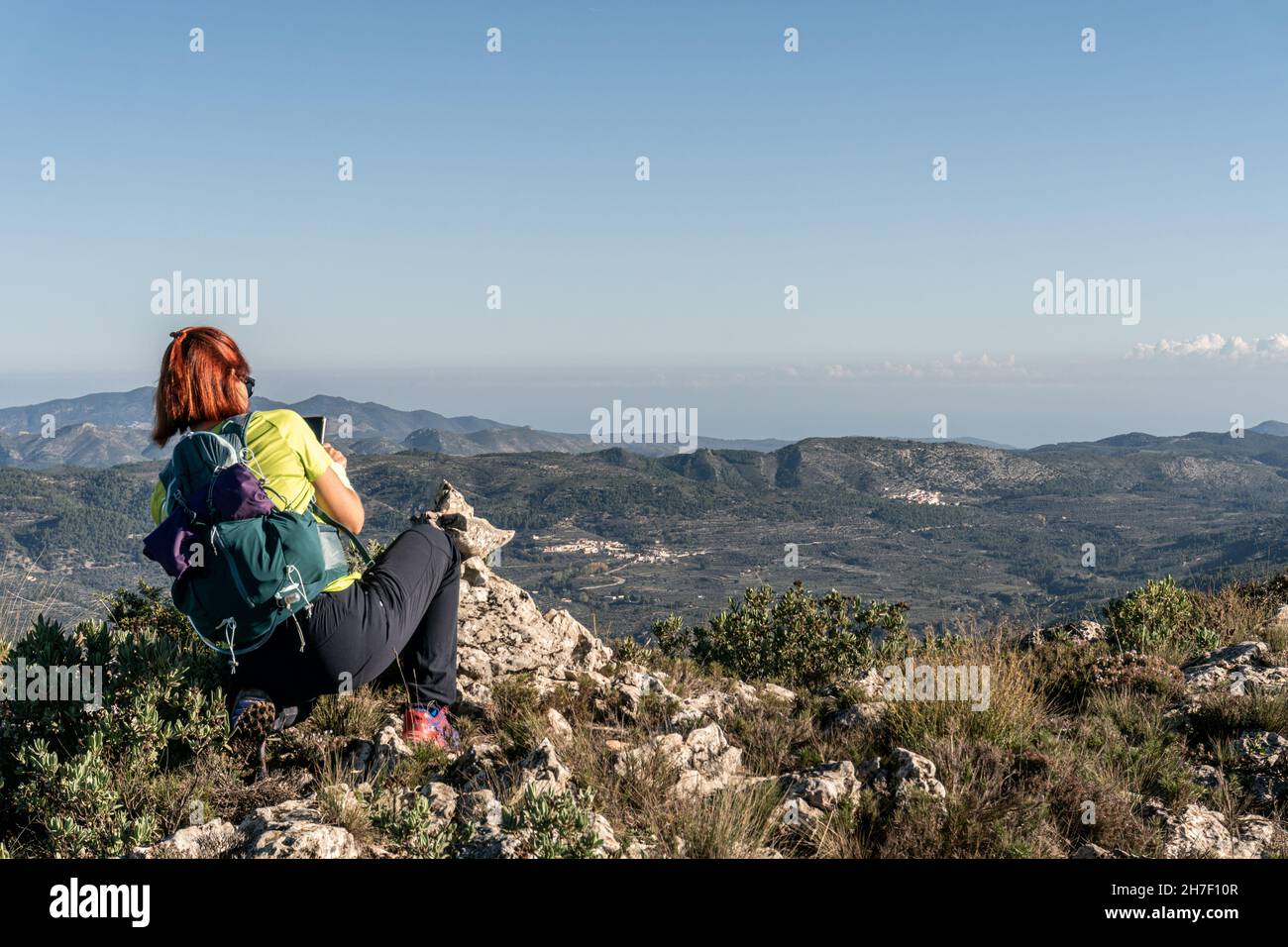 Female adventurous hiker sitting on the rocks taking a picture of the ...