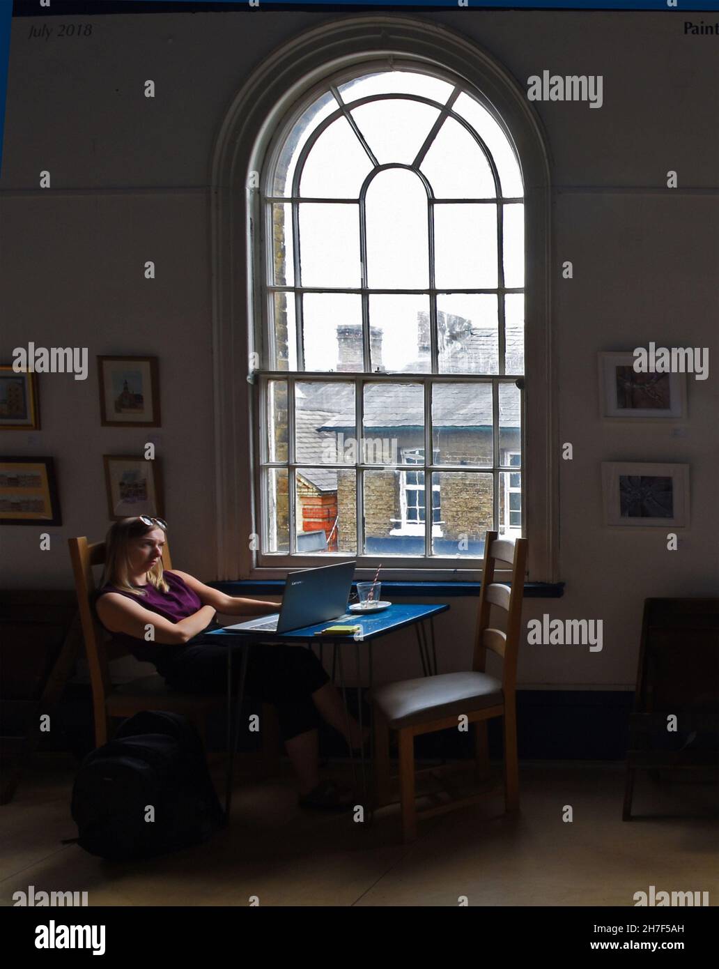 Gallery café interior with arched window paintings on wall and woman ...