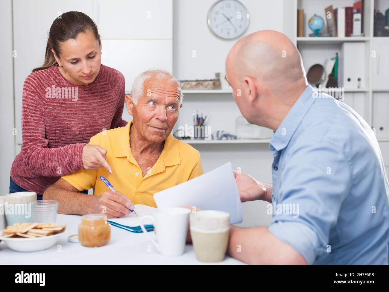 Adult children help an older father sign documents Stock Photo - Alamy