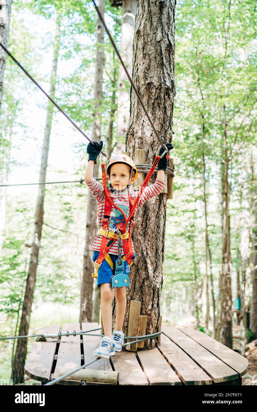 Boy stand on the zip line holding on to the safety cables Stock Photo ...