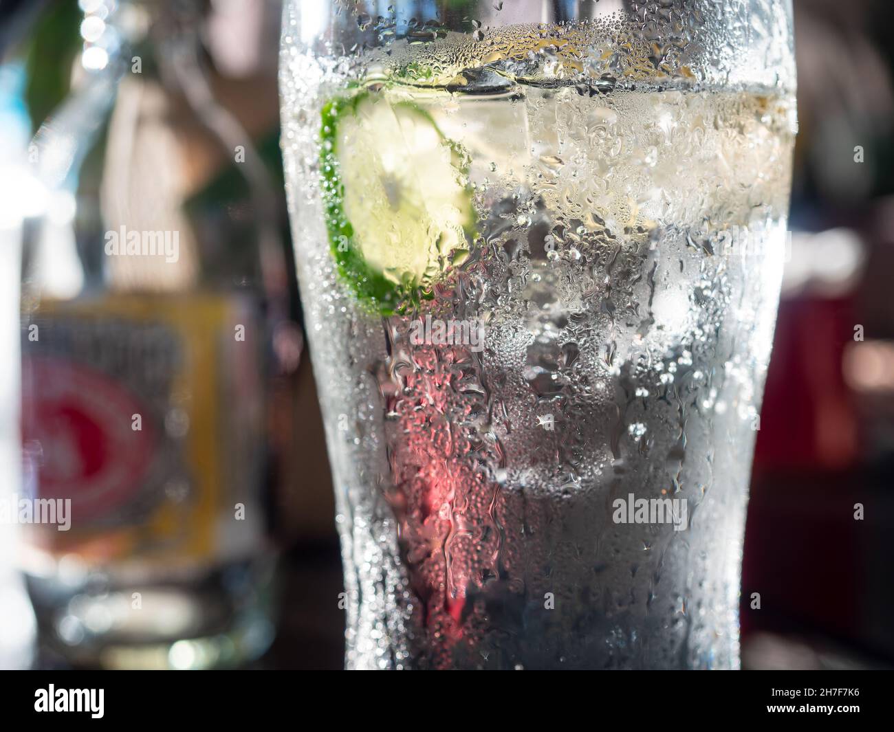 Glass of cold soda water with ice cubes and a slice of lime, dew on the ...