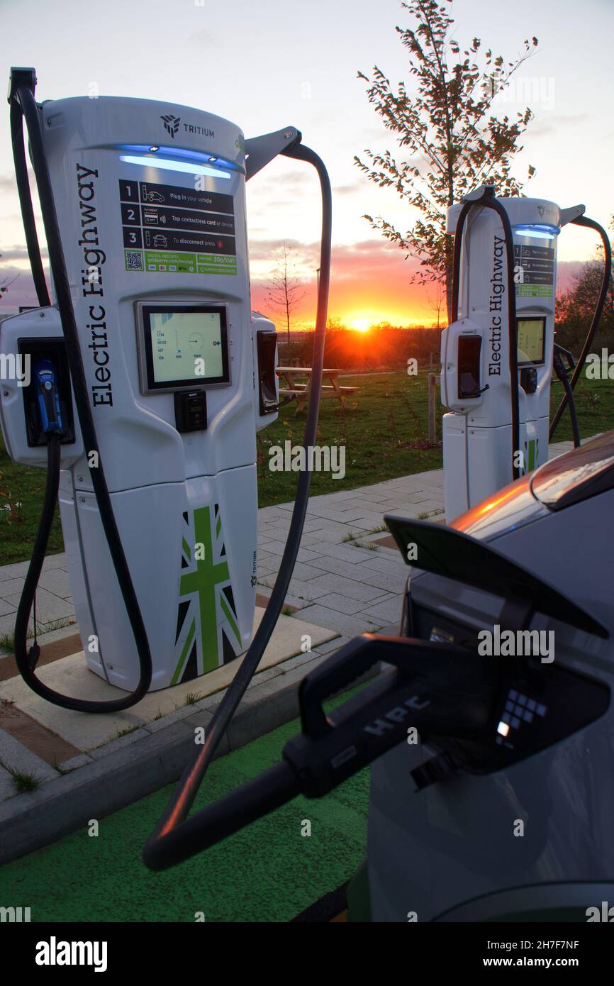 Electric vehicle plugged in and charging at sunset at a Gridserve ...