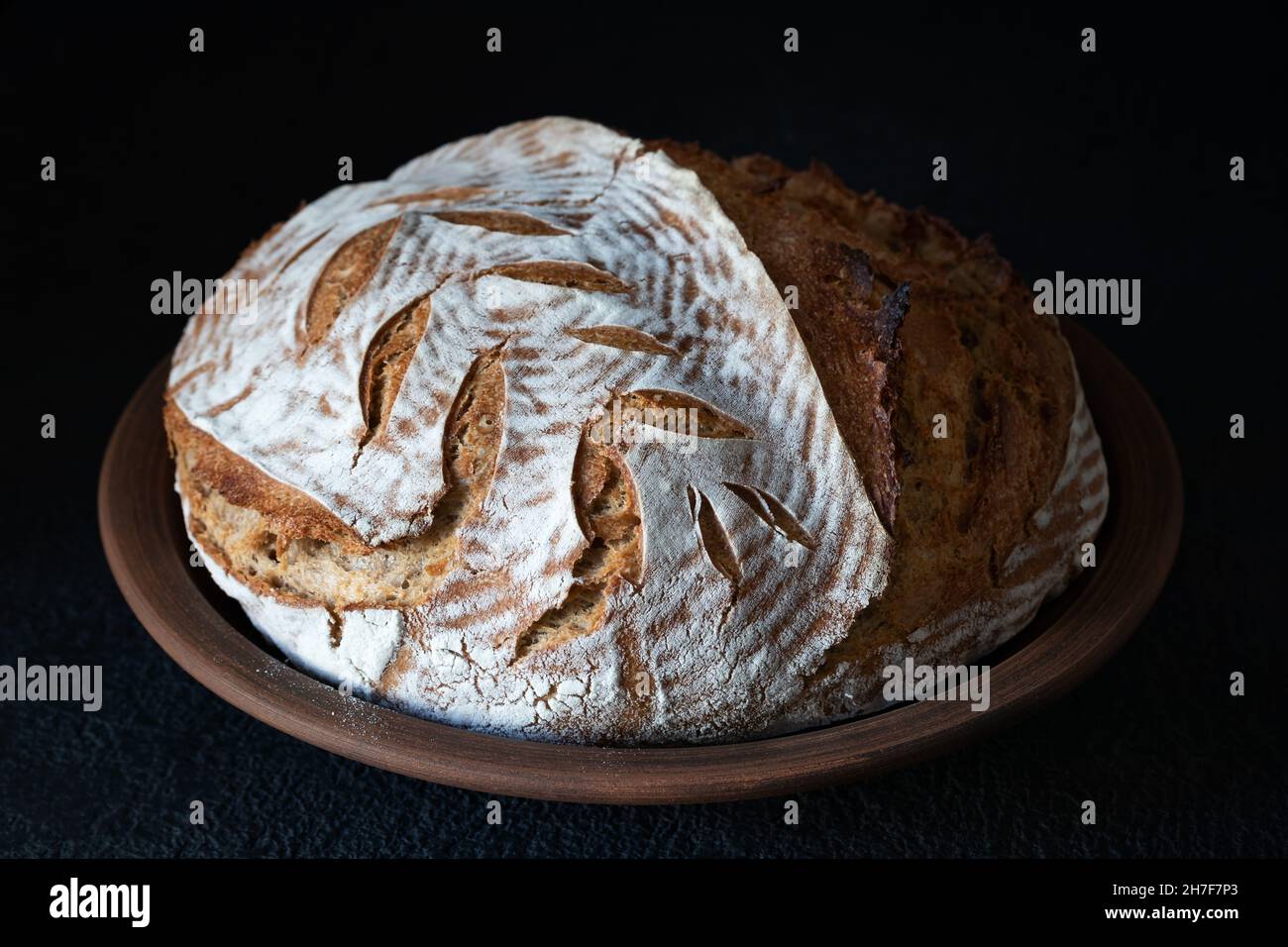 Homemade round dark bread with flour crust and painted spikelet on a ...