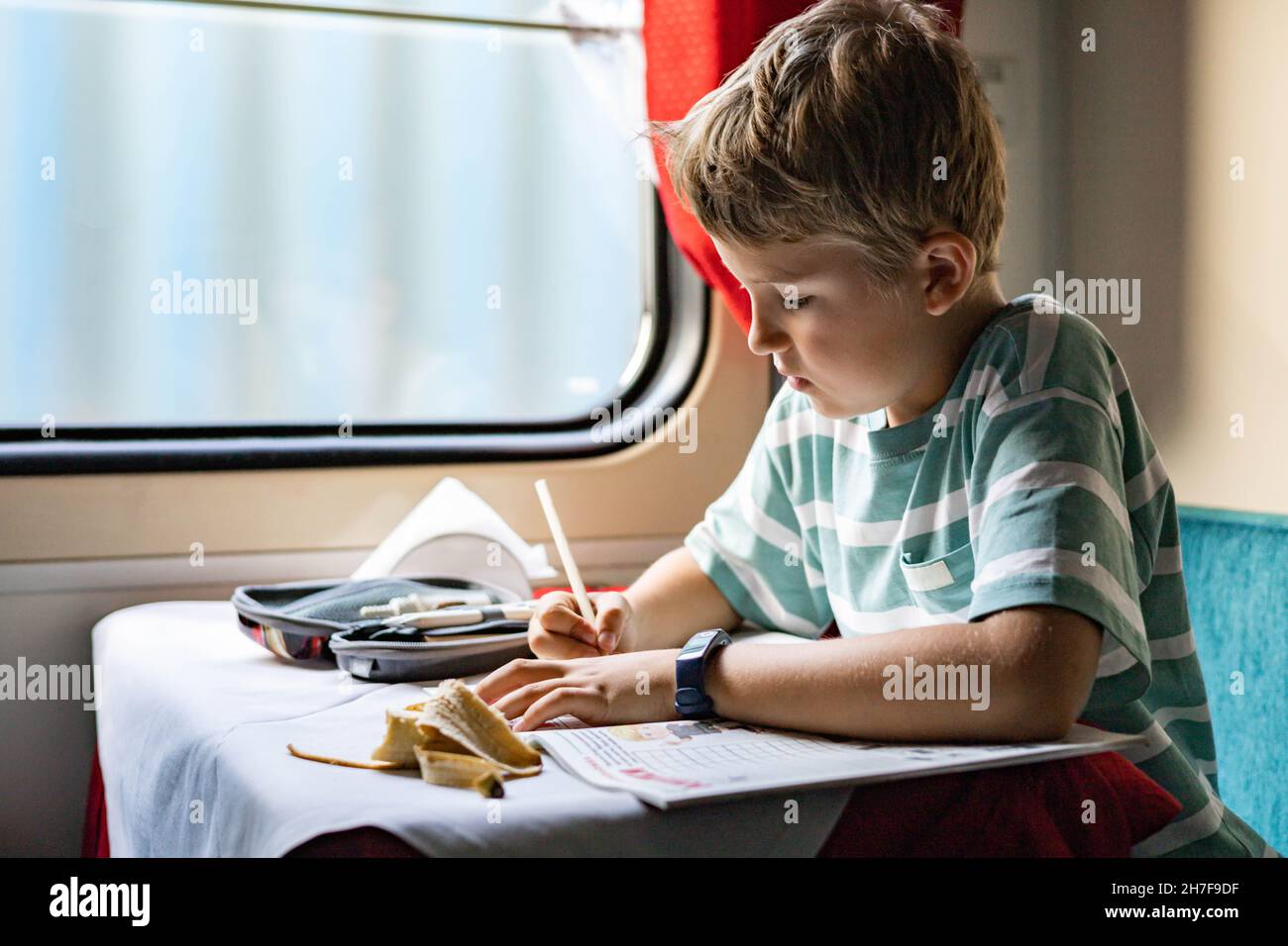 Focused male kid drawing writing paper notes enjoying travel by train ...