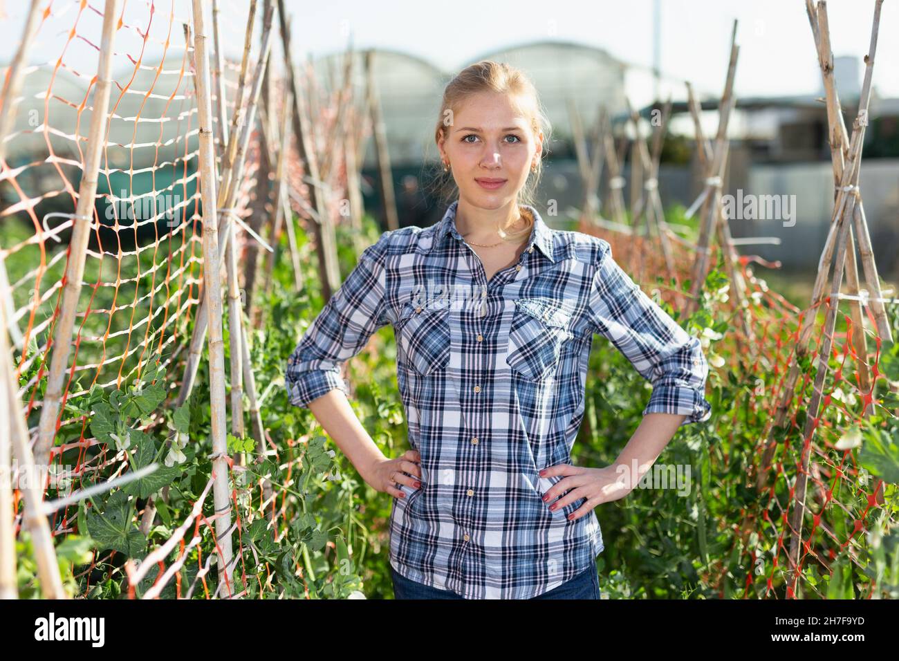 Girl gardener using mattock at land with green seedlings in garden ...