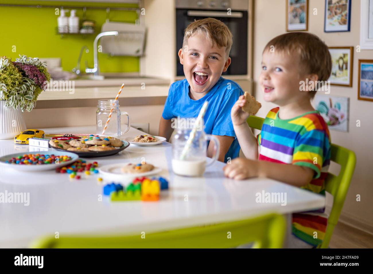 Funny male brothers eat cookies with round multi-colored sweets and ...