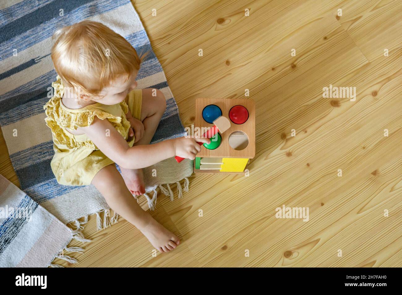 Happy girl toddler hitting wooden hammer on colored balls early ...