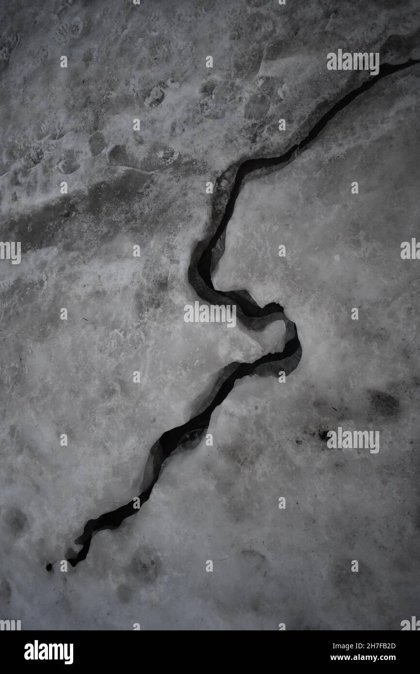 Close-up shot of a crack on the iced snow on the ground Stock Photo - Alamy