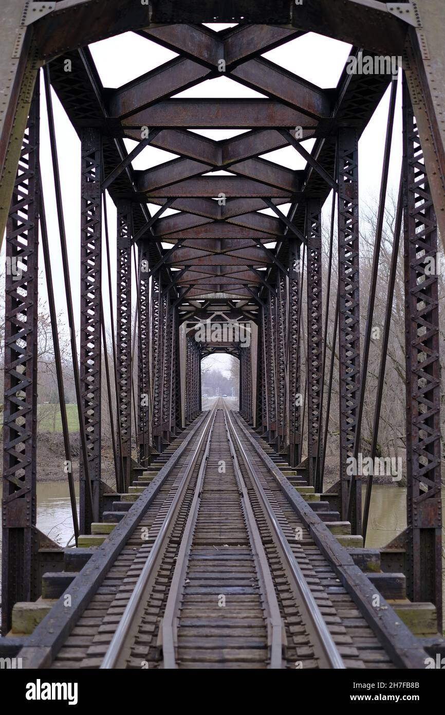 Perspective view of a metal railroad bridge on a river Stock Photo - Alamy