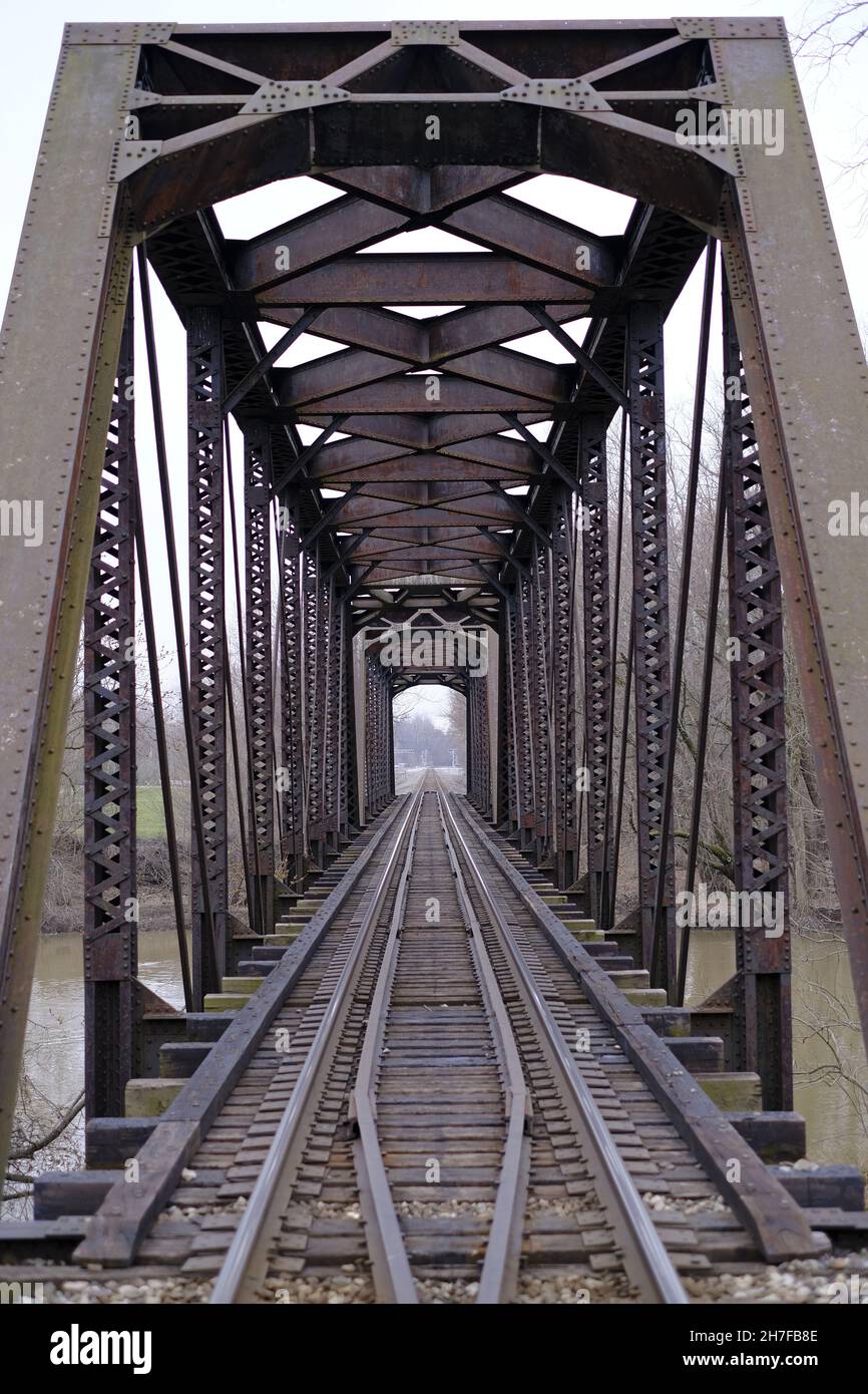 Perspective view of a metal railroad bridge on a river Stock Photo - Alamy