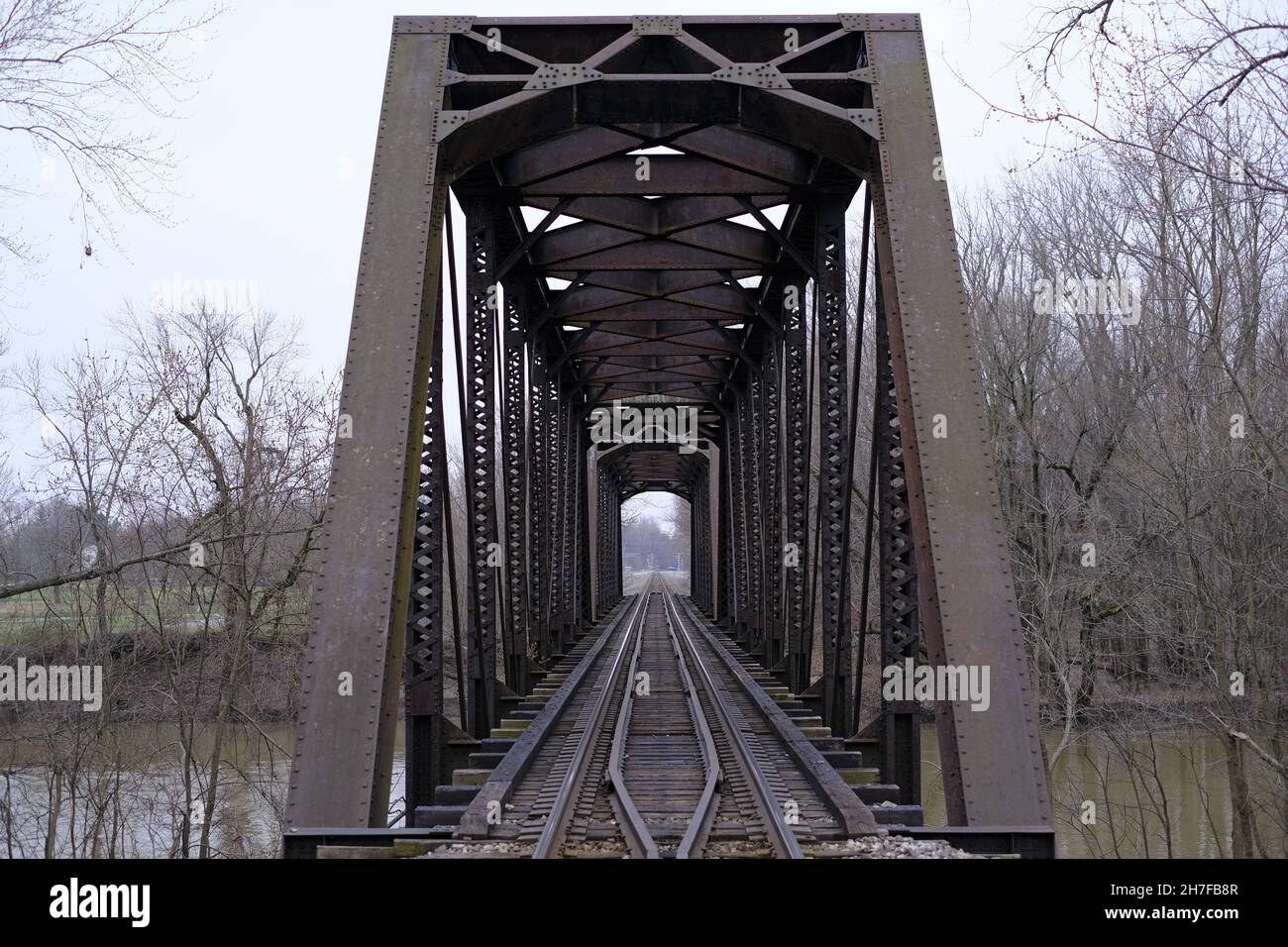 Perspective view of a metal railroad bridge on a river Stock Photo - Alamy