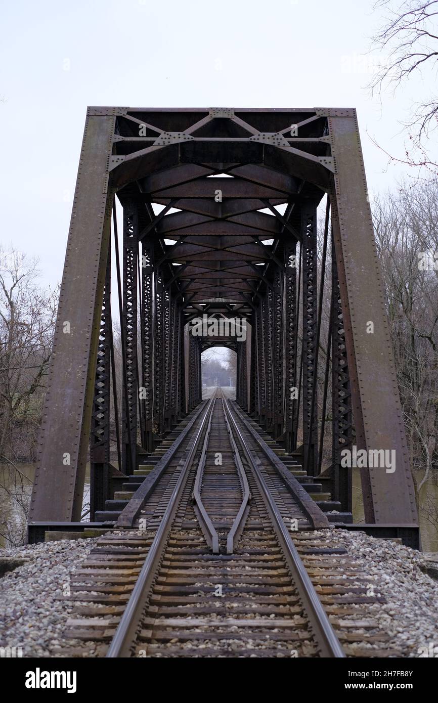 Perspective view of a metal railroad bridge on a river Stock Photo - Alamy