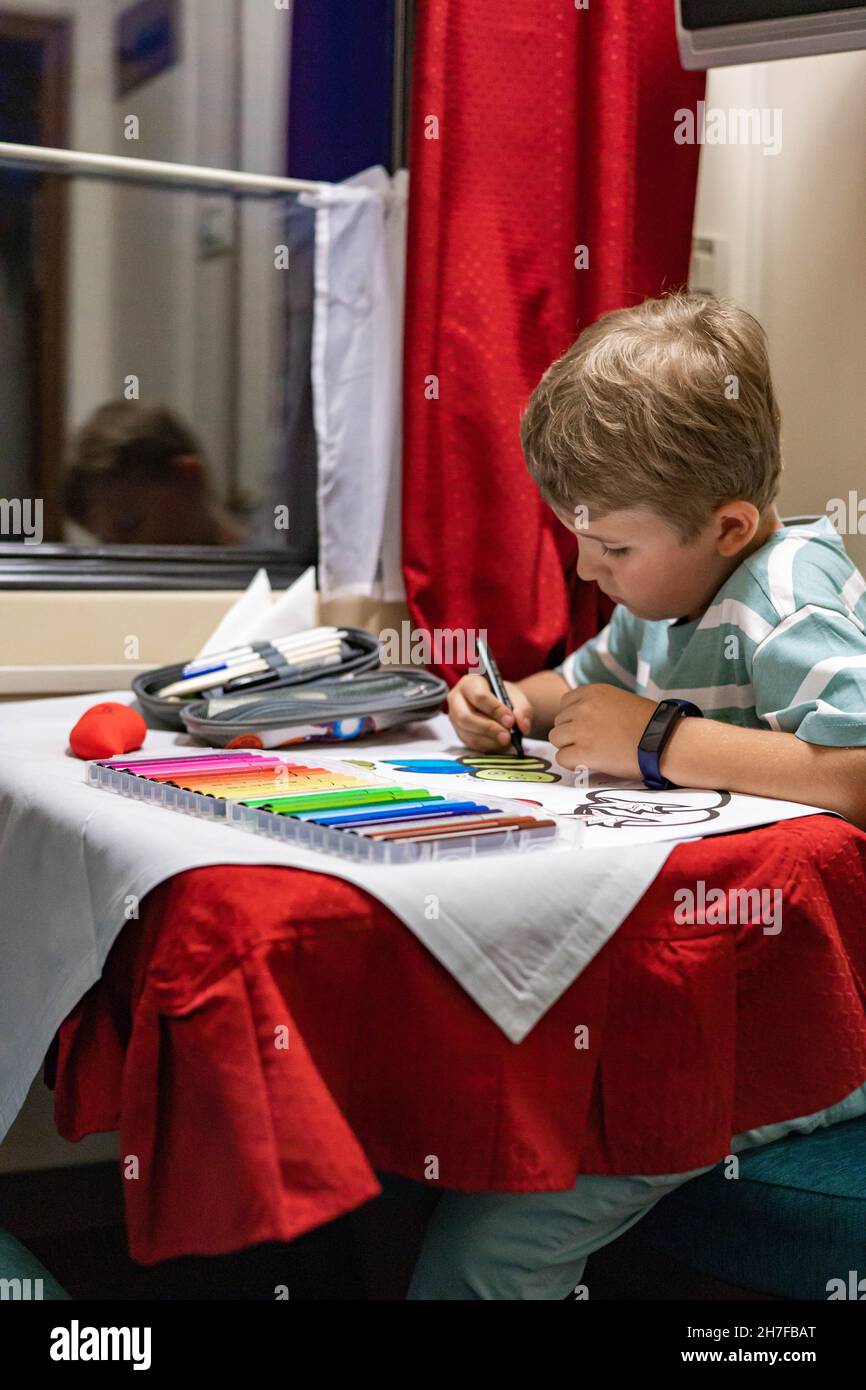 Focused male kid drawing writing paper notes enjoying travel by train ...