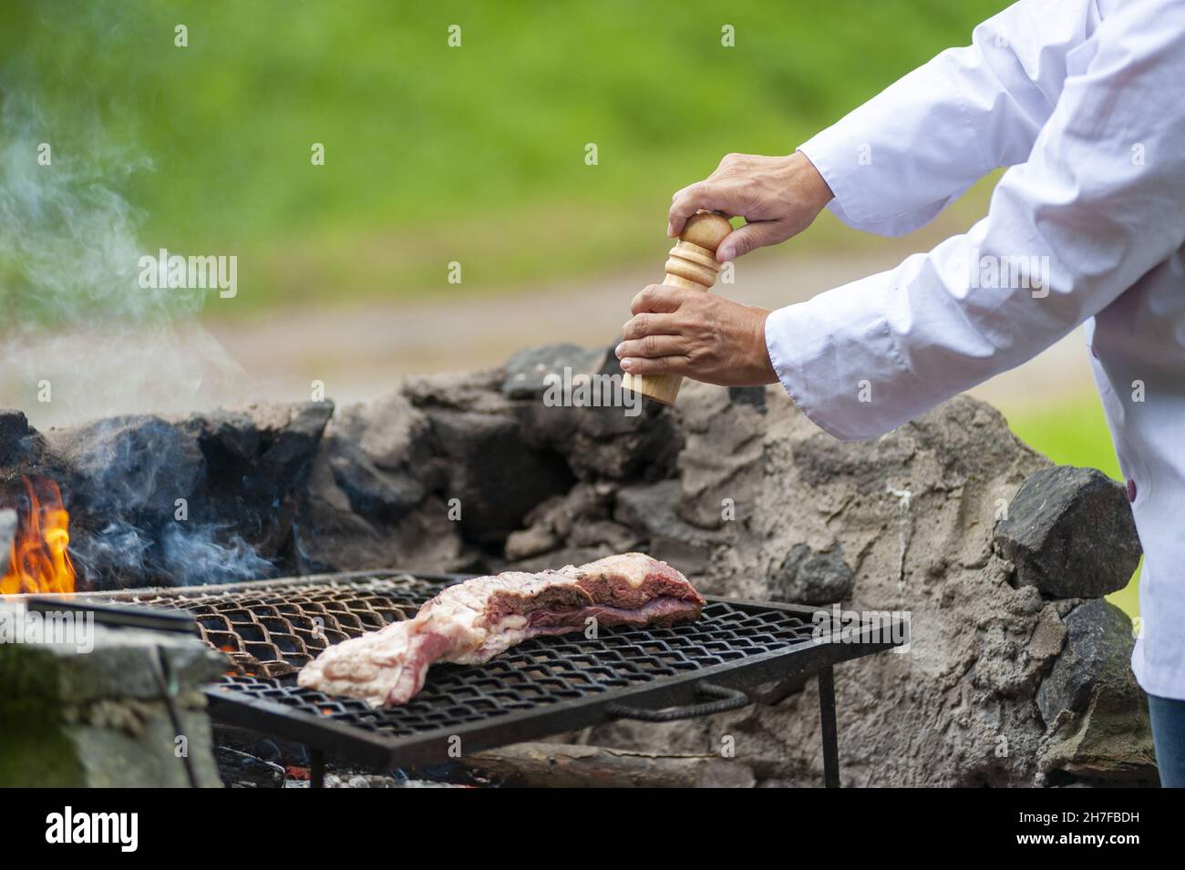 Chef pouring spices on barbecue on fire Stock Photo - Alamy