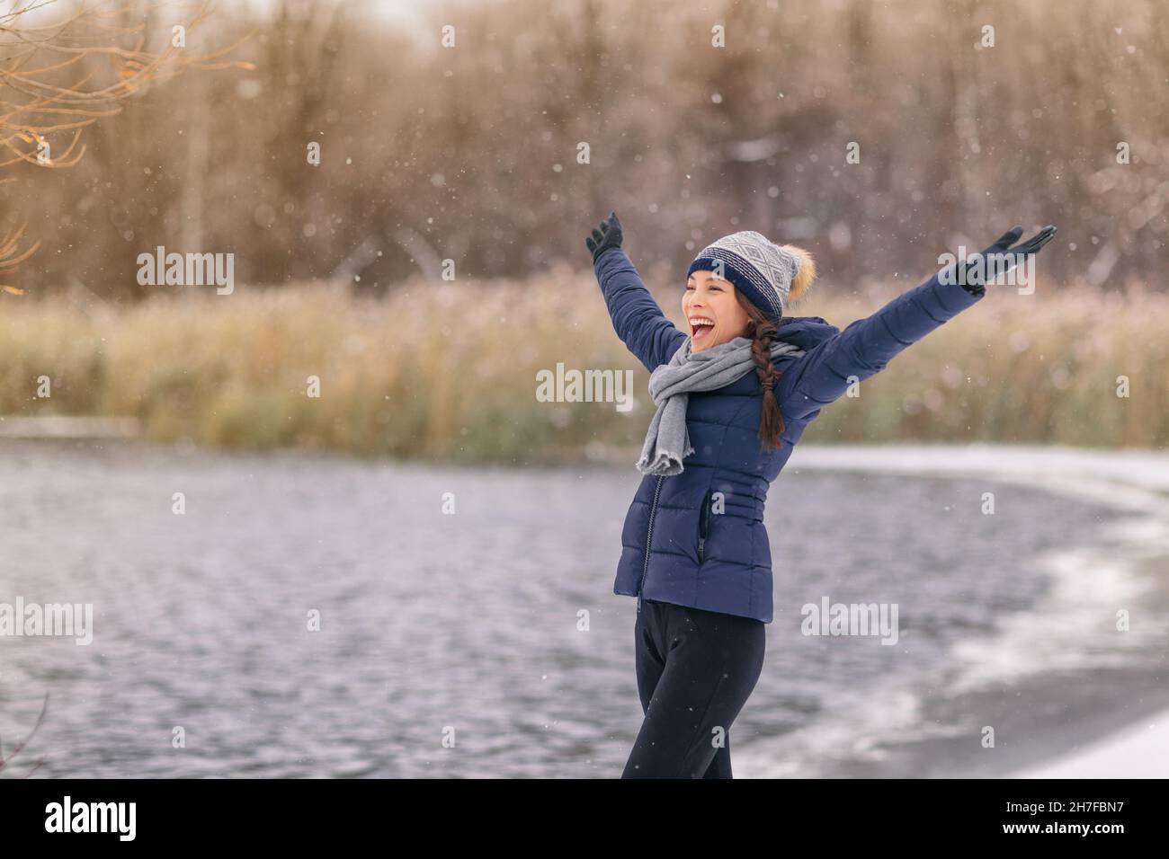 Happy winter snow fun Asian woman playing outside in snowy sunshine ...
