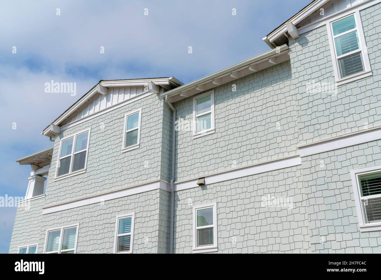 Low angle view of a two-storey house with light gray shingles siding ...