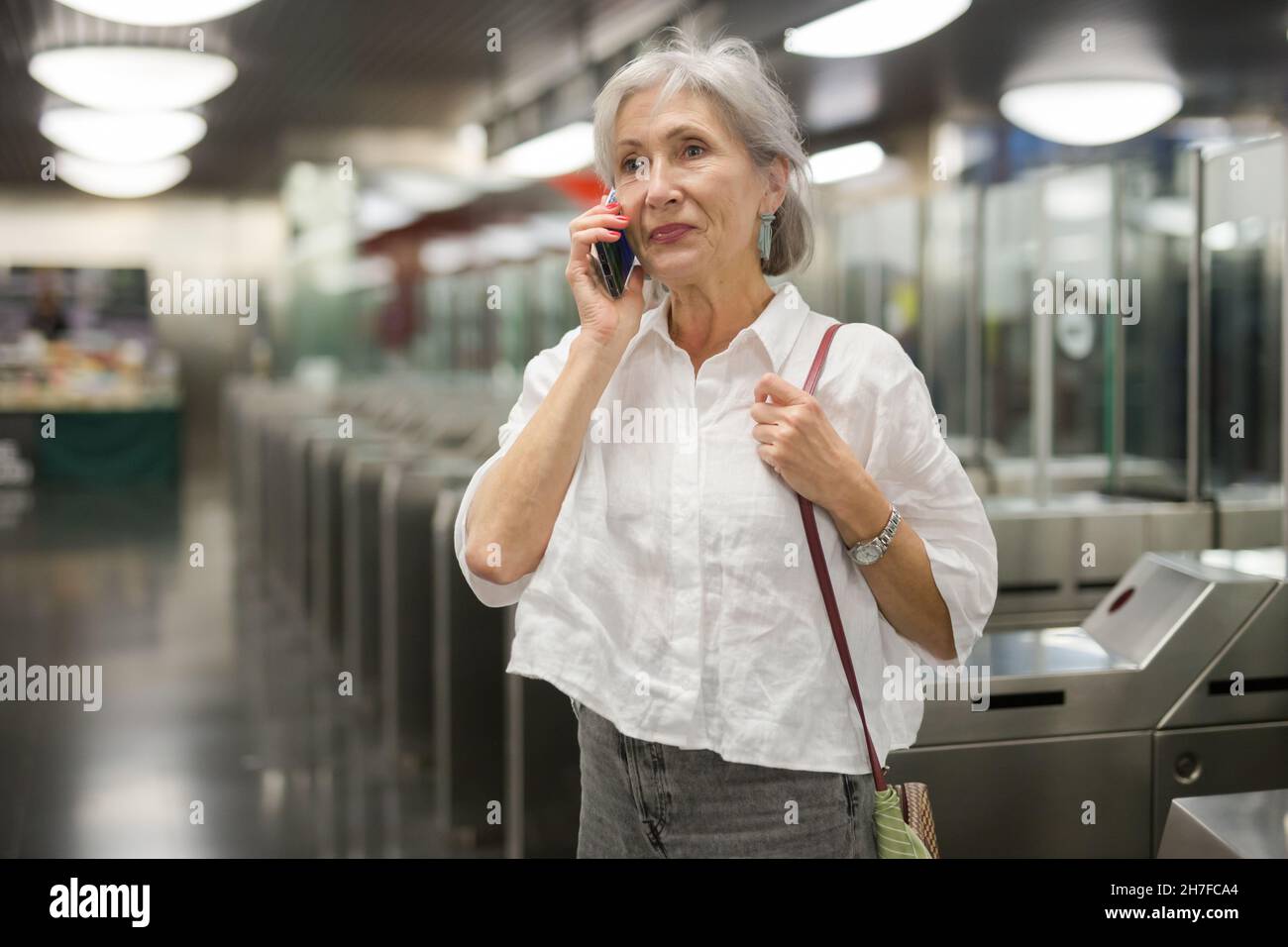 Lady standing and talking on phone near ticket barriers Stock Photo - Alamy