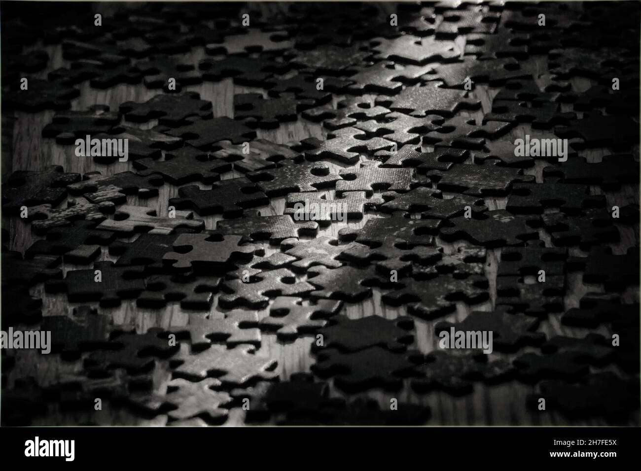 Grayscale closeup shot of a light ray shining on a pile of puzzle ...