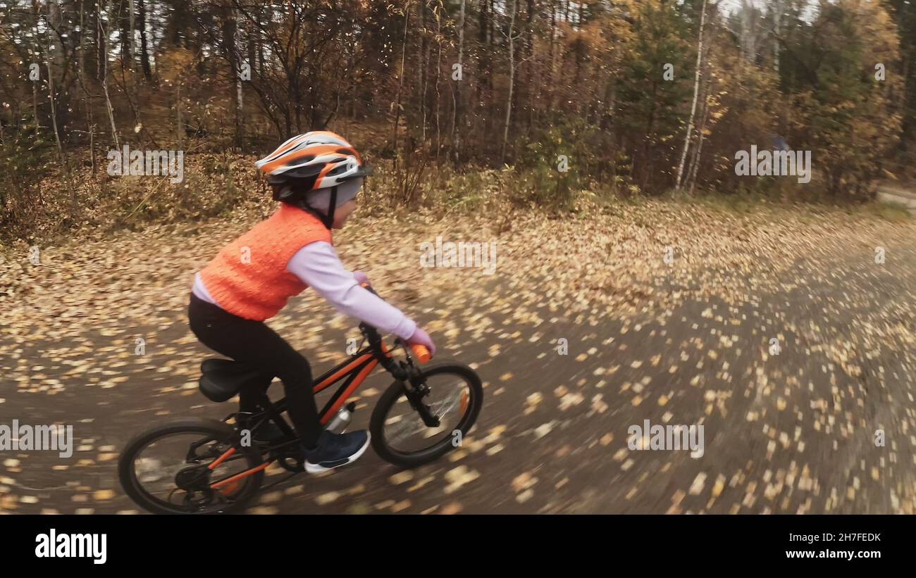 One caucasian children rides bike road in autumn park. Little girl ...