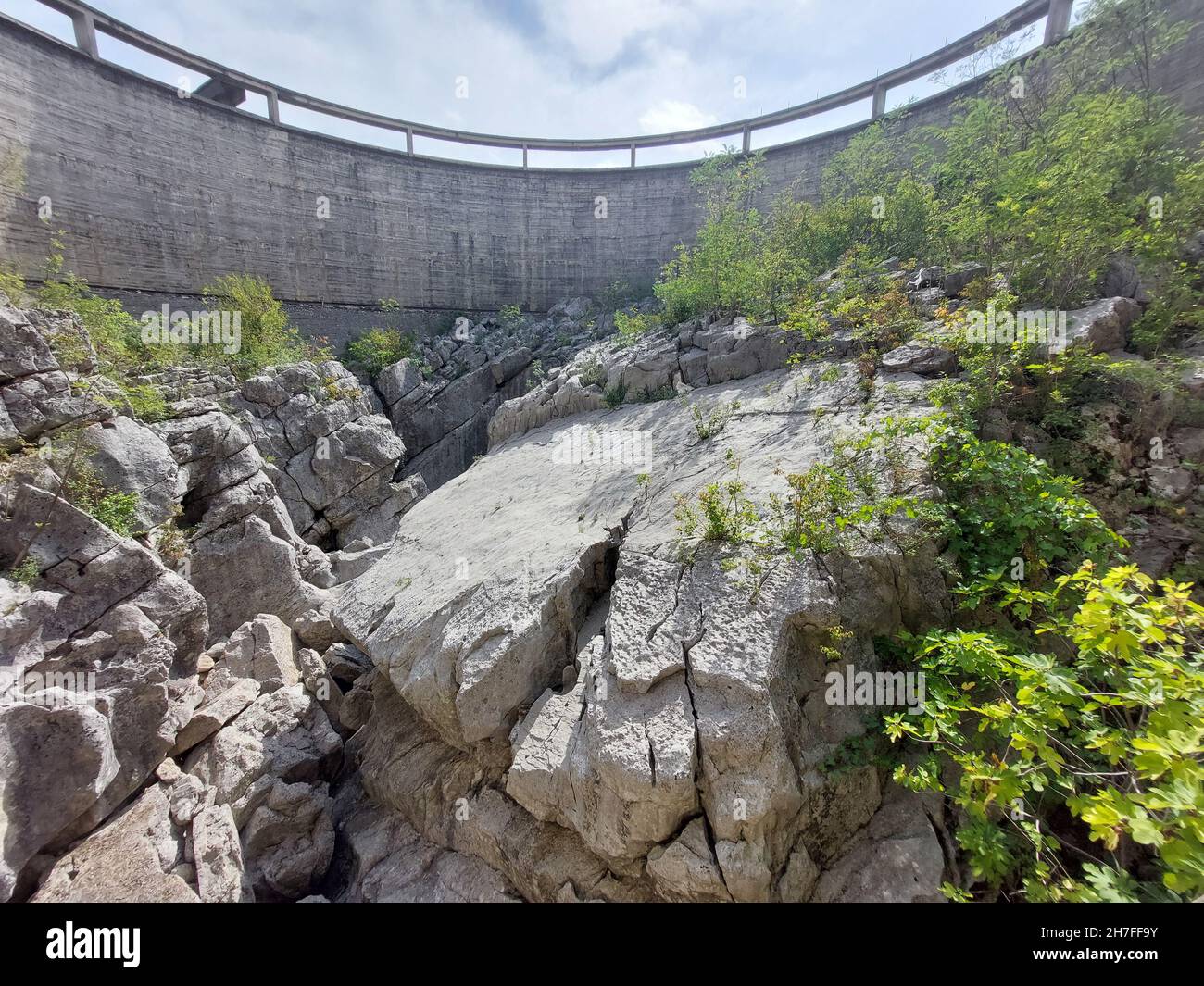 Old dam surrounded by rocks under the sunlight and a cloudy sky Stock ...