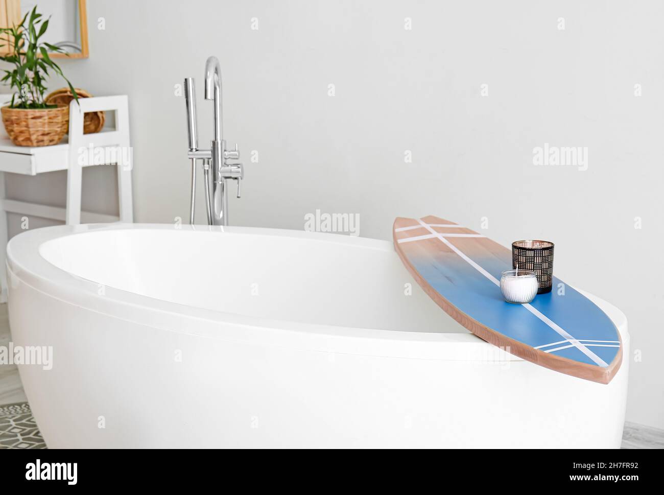 Bathtub with surfboard and aroma candles in modern interior of bathroom ...