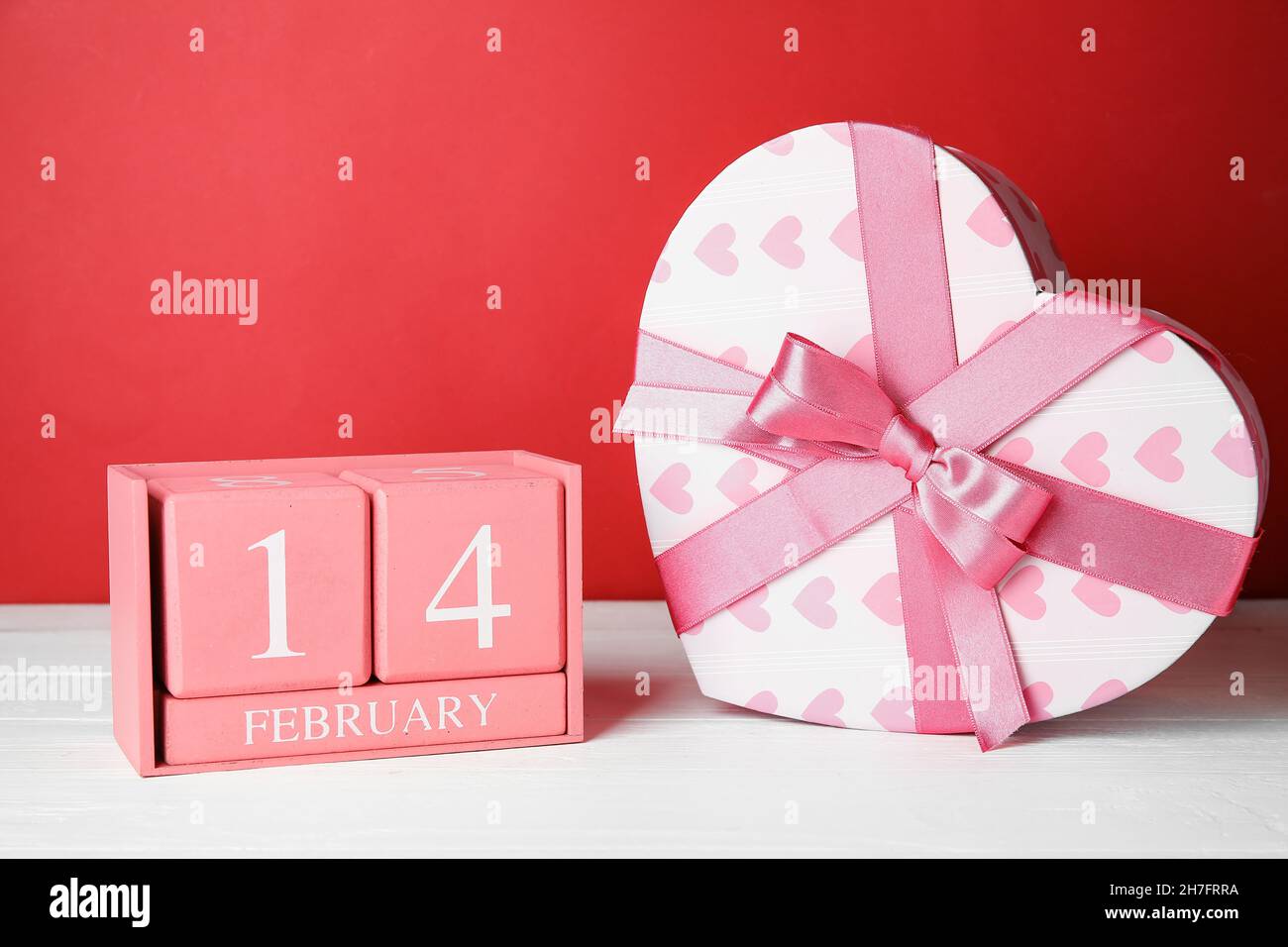 Calendar with date of Valentines Day and gift box on table against ...
