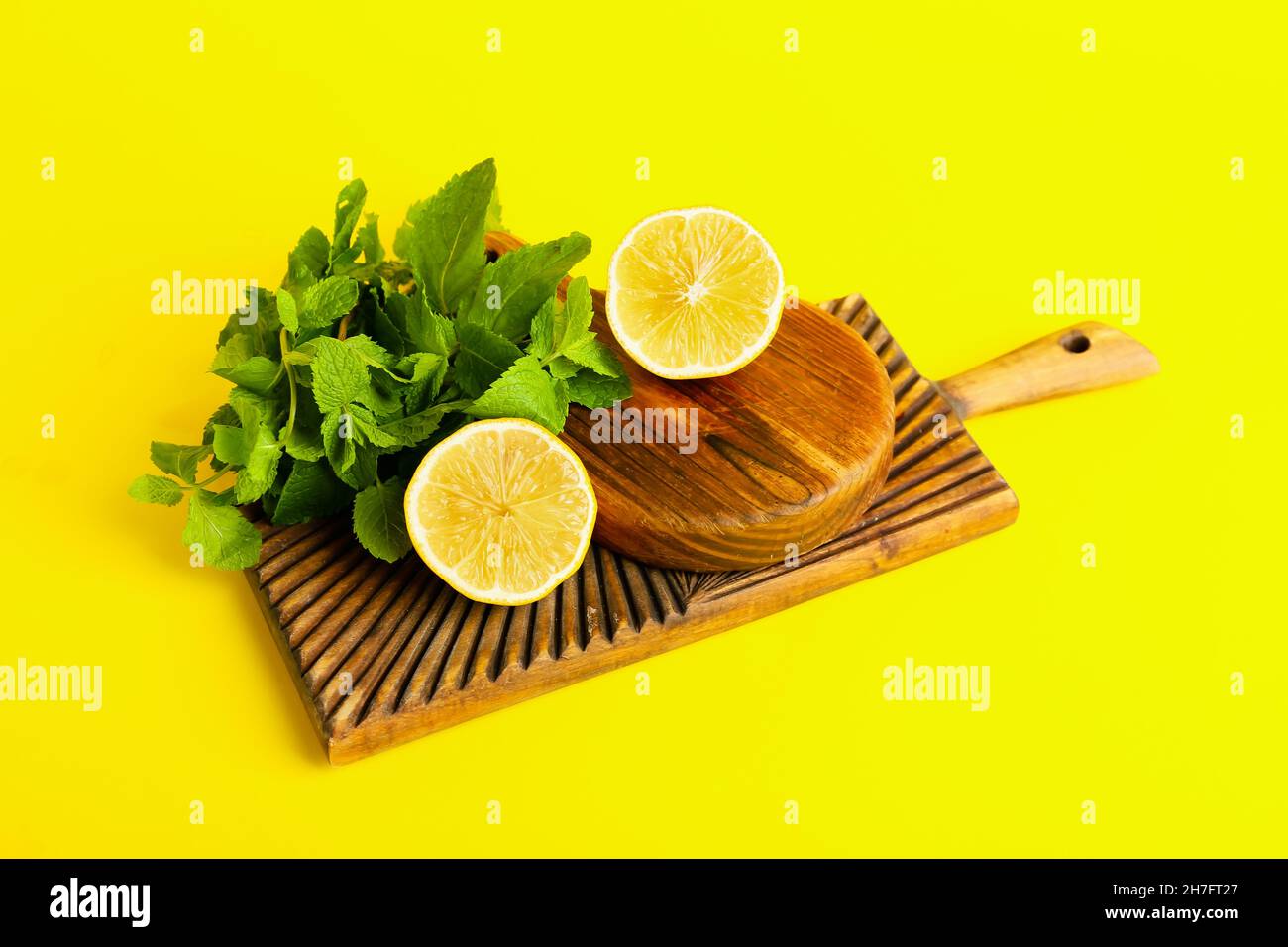 Wooden boards with bunch of fresh mint and cut lemon on color ...