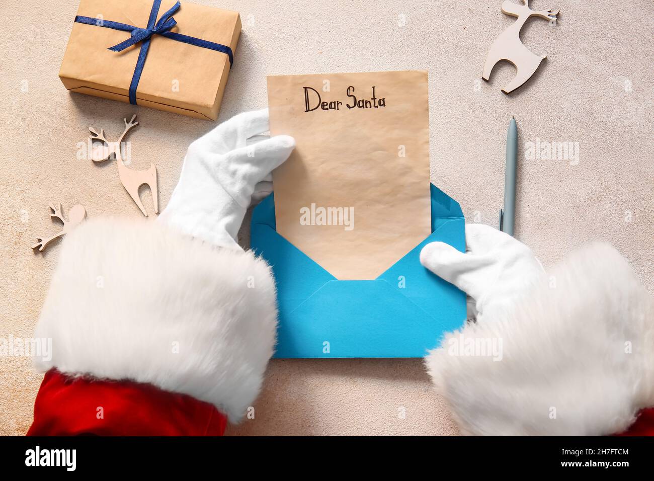 Santa Claus holding wish list letter with text DEAR SANTA on light ...