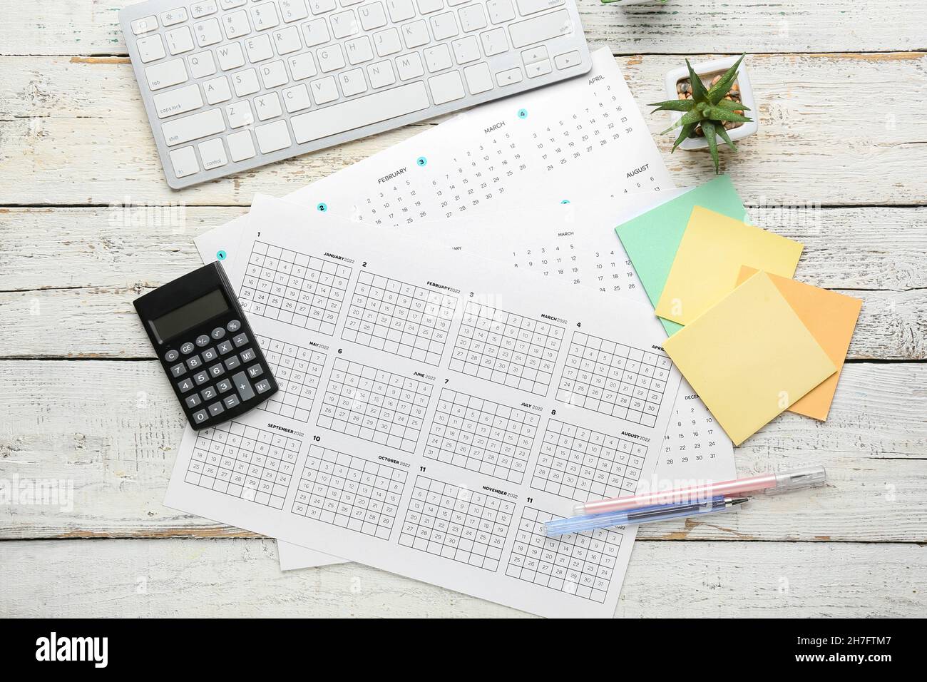 Paper calendars with stationery and computer keyboard on white wooden ...