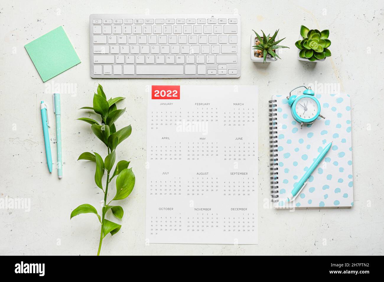 Paper calendar with stationery, alarm clock and computer keyboard on ...