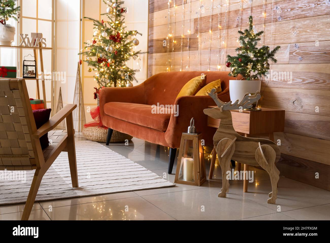 Interior of stylish living room with red sofa, Christmas trees and ...