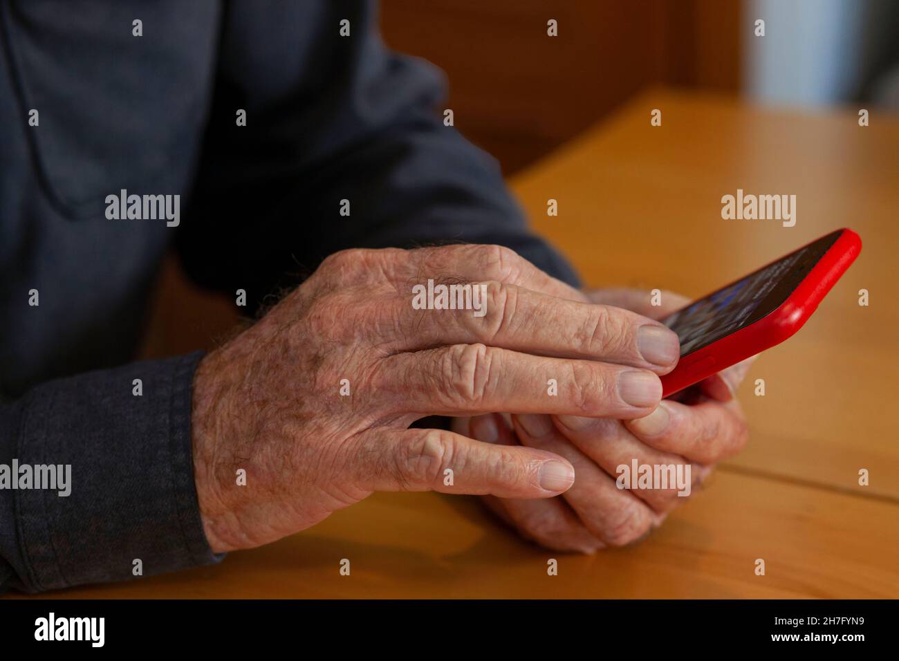 A close up of the hands of an elderly man's hands holding a cell phone ...