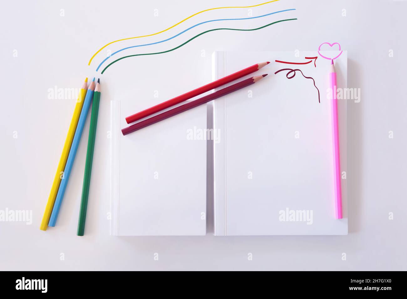 Top view of blank notebook and colored pencils drawing lines, arrows ...