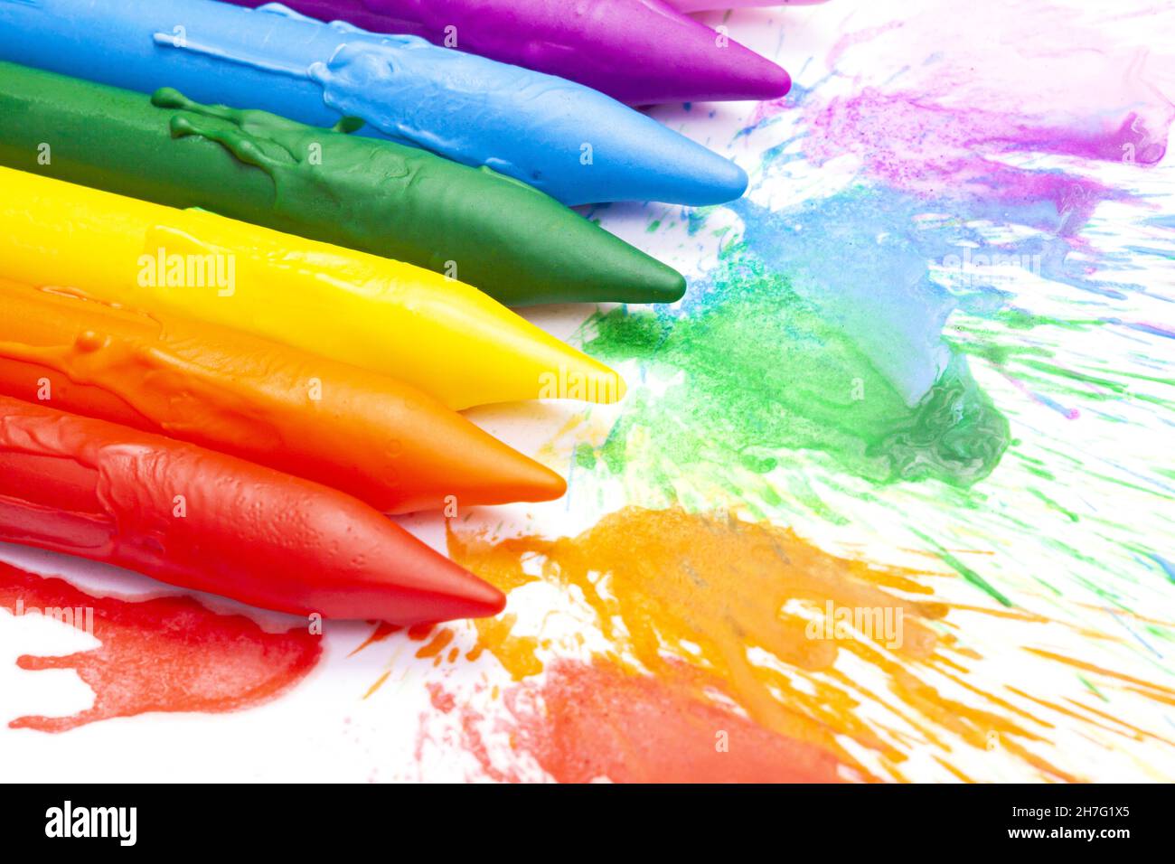 Closeup shot of rainbow-colored school crayons with burst ink on a ...