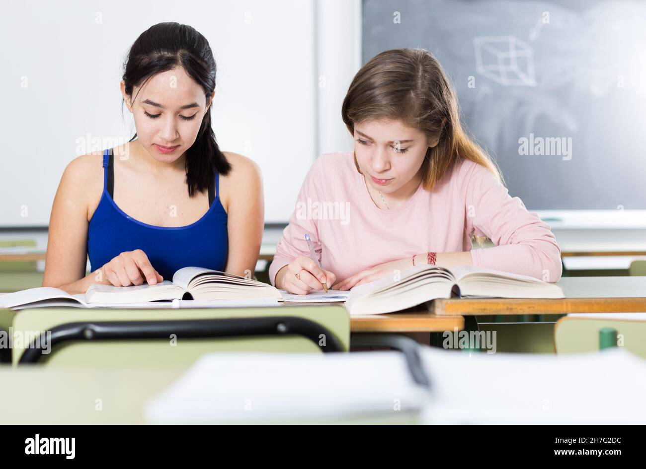 Two girls are sitting at the desk and writing homework Stock Photo - Alamy