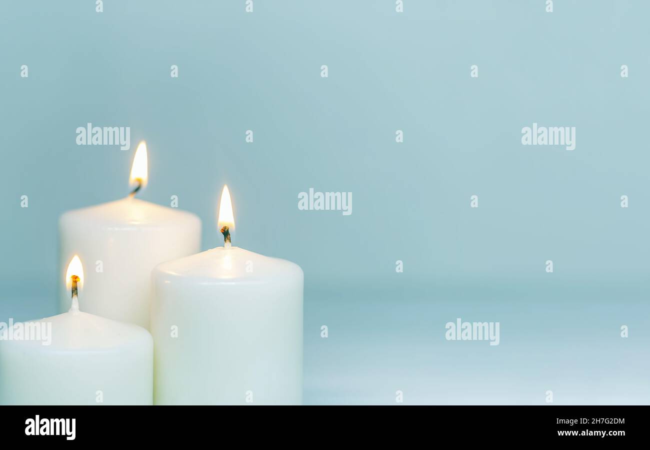 Panorama of three white candles burning on white gradient background ...